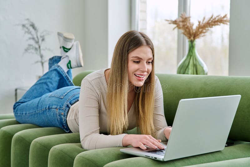Young Woman Lying on Sofa at Home Using Laptop Stock Photo - Image of ...