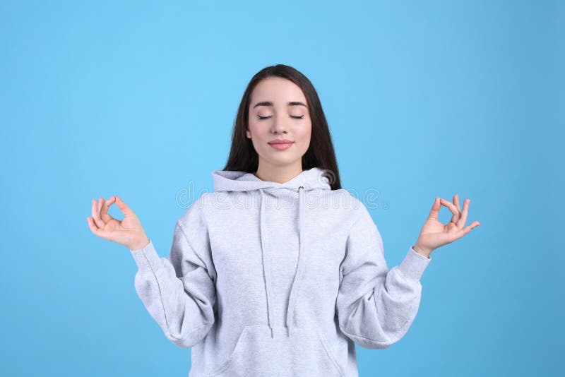 Young Woman Meditating on Light Blue Background. Stress Relief Exercise ...