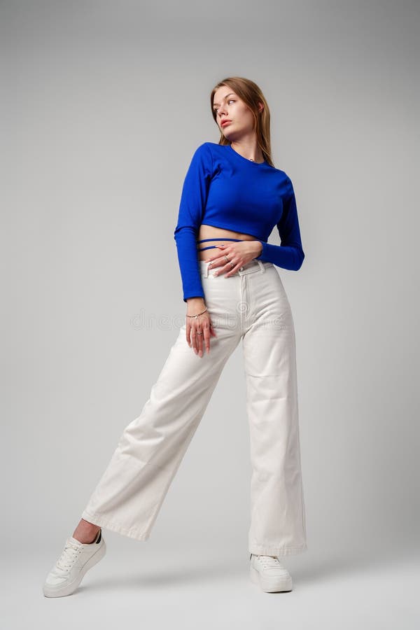 Young Woman Model in Blue Top and White Pants Posing on White ...