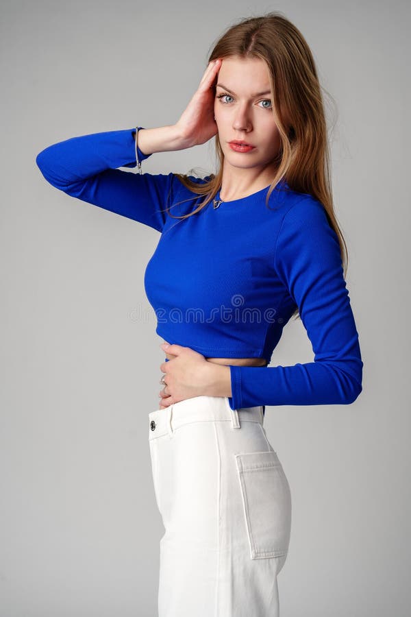 Young Woman Model in Blue Top and White Pants Posing on White ...