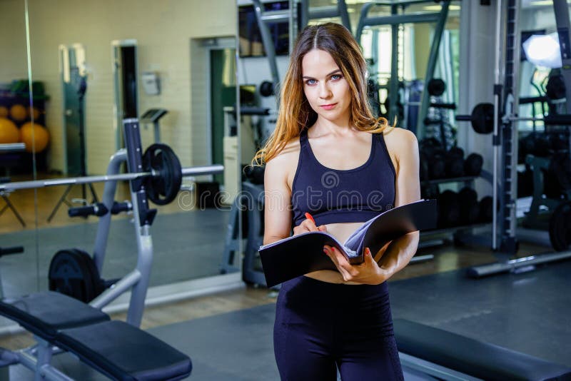 Young Woman Personal Trainer Writes the Training Plan in a Notebook ...