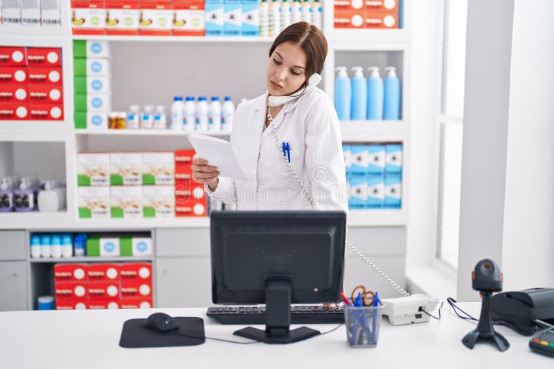 Young Woman Pharmacist Talking on Telephone Working at Pharmacy Stock ...