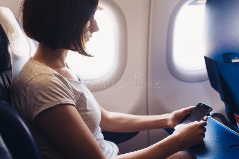 Young Woman On A Plane With A Smartphone In Her Hands Stock Image