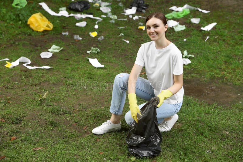 Young Woman with Plastic Bag Collecting Garbage on Green Grass Outdoors ...