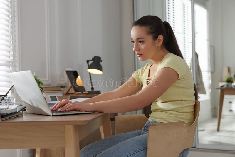 Young Woman with Poor Posture Using Laptop at Table Indoors Stock Photo ...