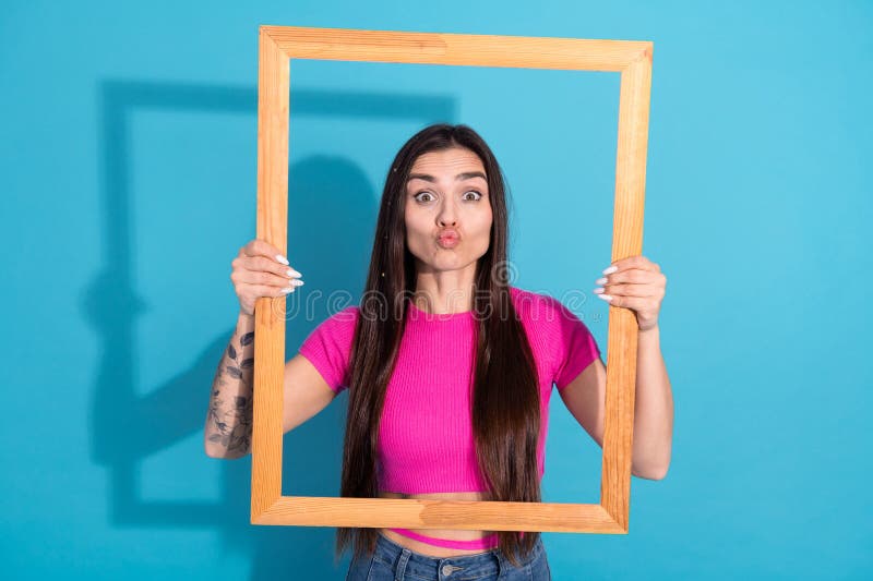 Young Woman Holding a Wooden Frame and Making a Playful Face Against a ...