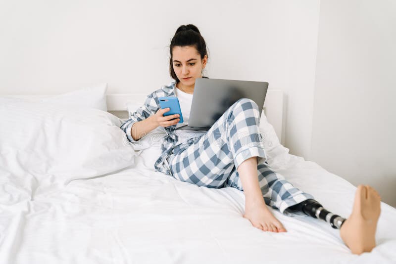 Young Woman with Prosthesis Using Gadgets while Resting on Bed Stock ...
