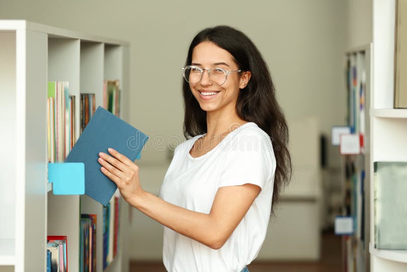 Young Woman Putting Book on Shelf Stock Photo - Image of library ...