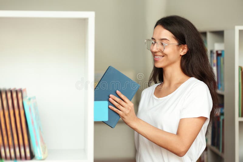 Young Woman Putting Book on Shelf Stock Photo - Image of books ...