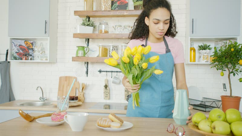 Young Woman is Putting Flowers in a Vase on the Dining Table Stock ...