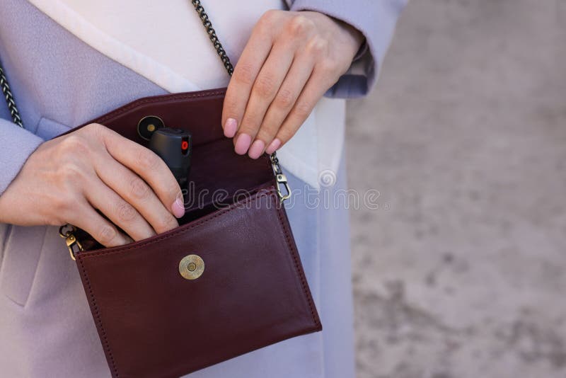 Young Woman Putting Pepper Spray into Bag Outdoors, Closeup. Space for ...