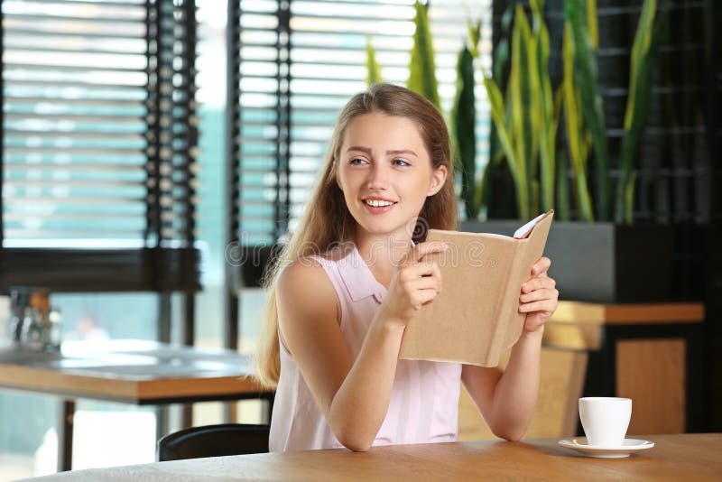 Young Woman Reading Book in Cafe Stock Image - Image of book, portrait ...