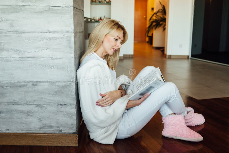 Young Woman Reading Book on Floor Near Light Wall Stock Image - Image ...