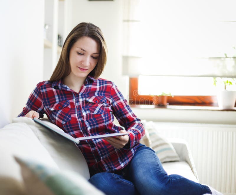 Young Woman Reading Book on Sofa Relaxing at Home Stock Photo - Image ...