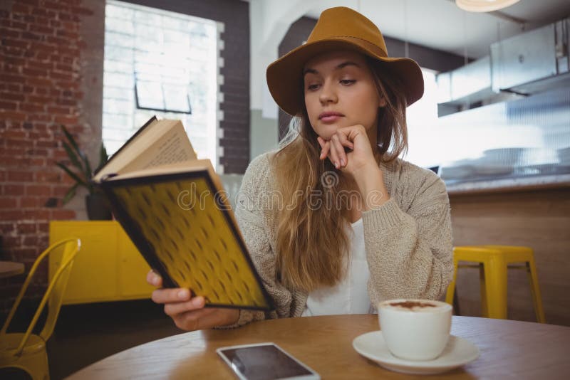 Woman reading book in cafe stock photo. Image of caucasian - 99479738