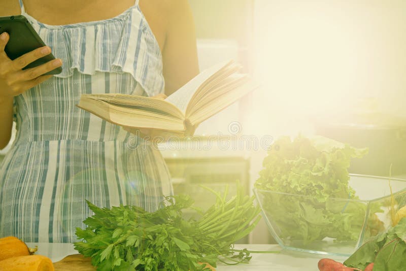 Young Woman Reading Cookbook in the Kitchen, Looking for Recipe Stock ...