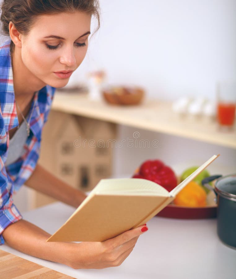 Young Woman Reading Cookbook in the Kitchen, Looking for Recipe Stock ...