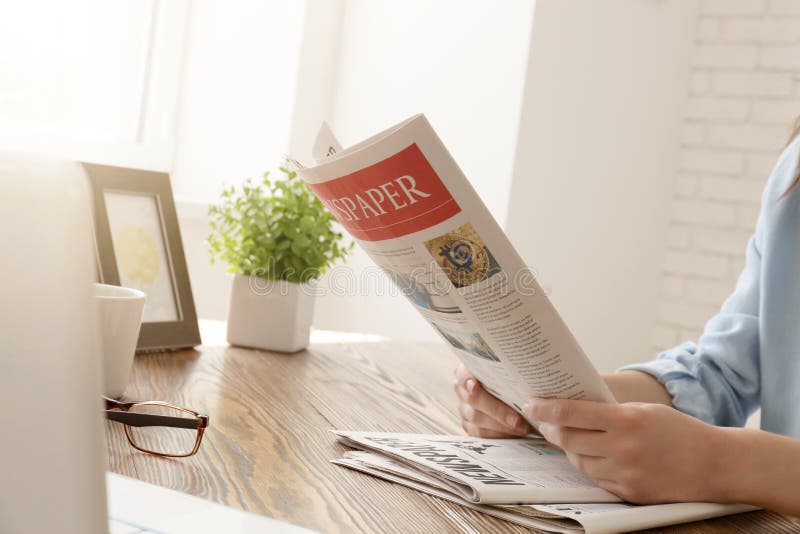 Young Woman Reading Newspaper at Table Indoors Stock Image - Image of ...