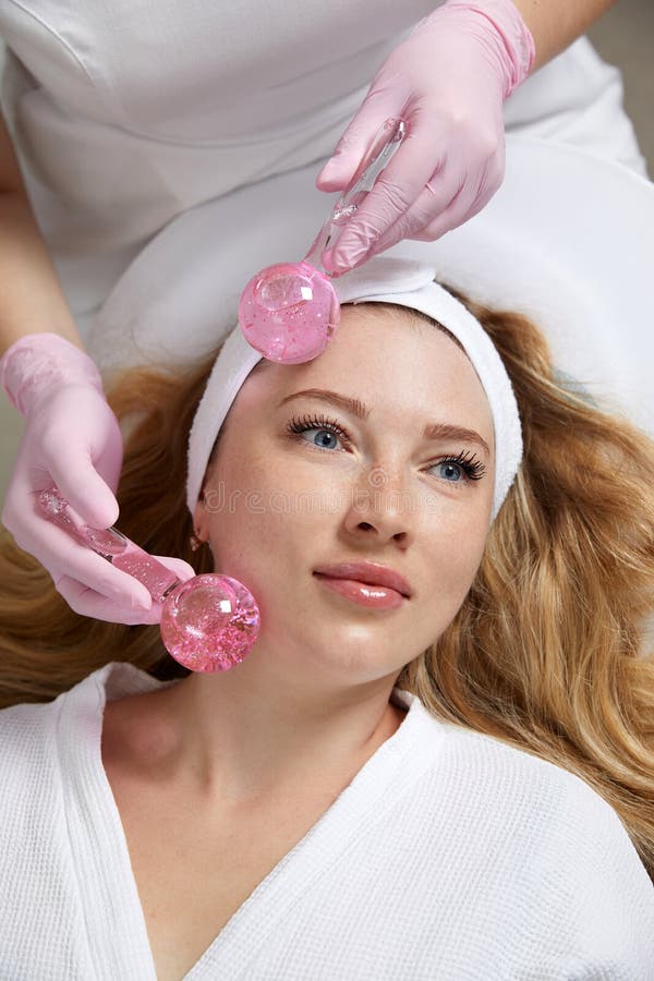 Young Woman Receiving Facial Massage With Glass Balls In Beauty Salon