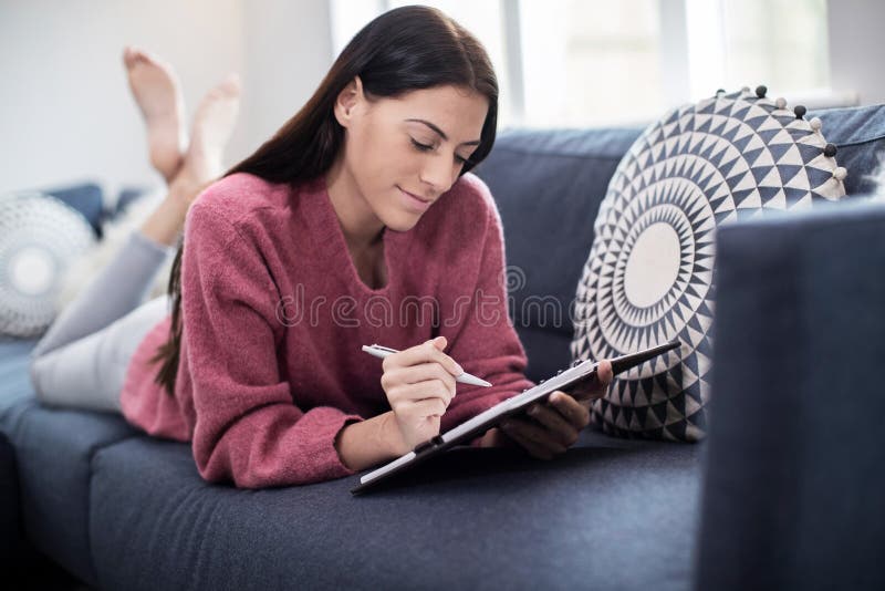 Young Woman Relaxing on Sofa at Home Writing in Journal Stock Image ...