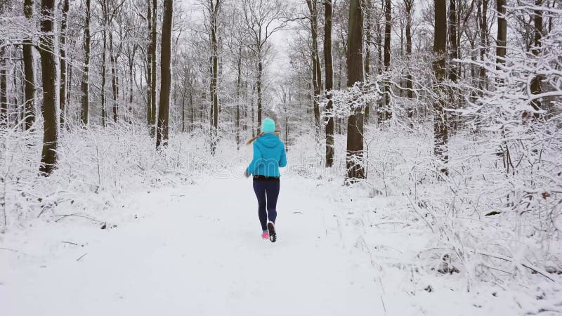 Young Woman Running Down a Path in the Winter Woods through Snow Stock ...