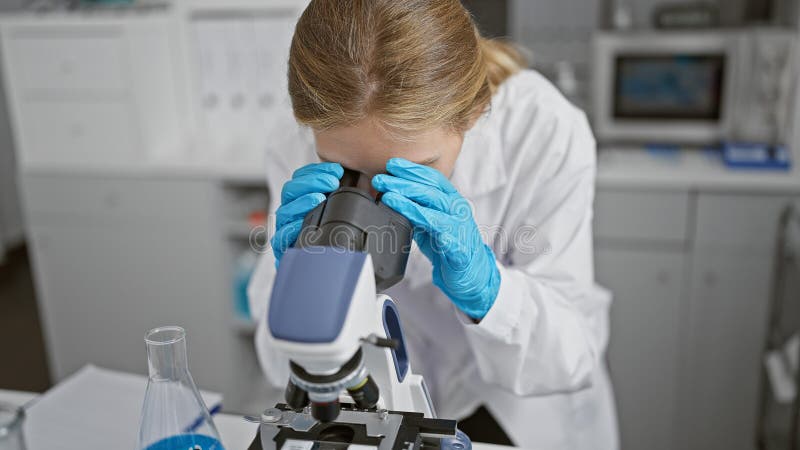 A Young Woman Scientist Observing Samples through a Microscope in a ...