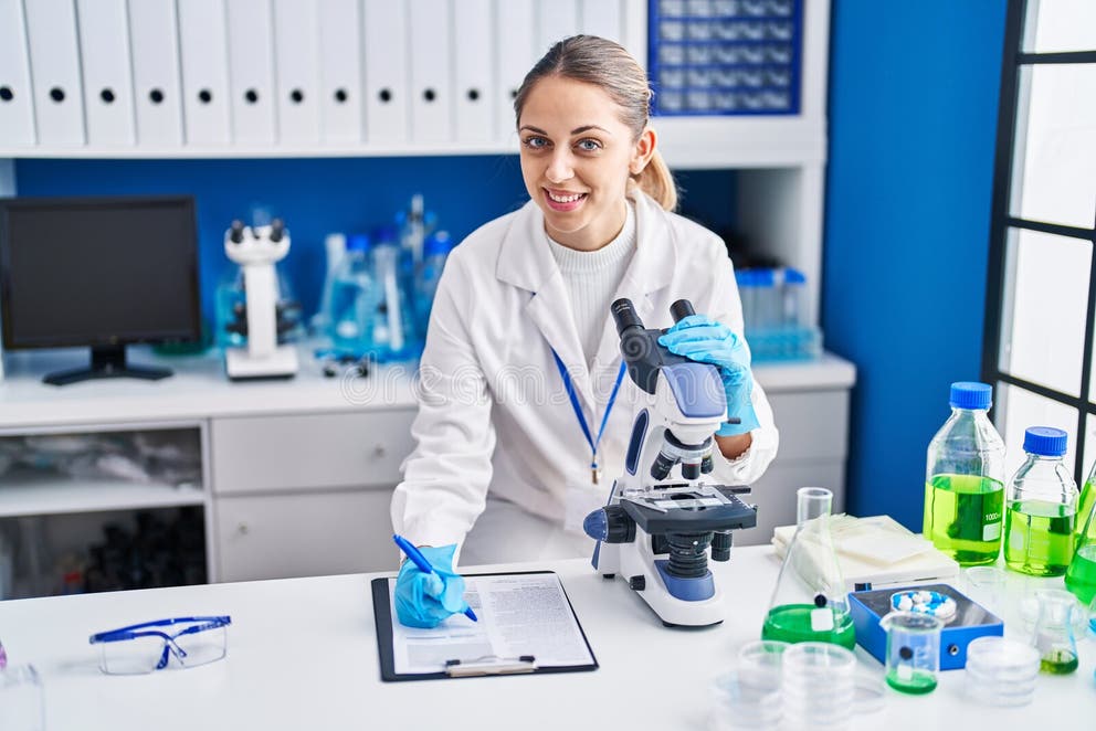 Young Woman Scientist Using Microscope Writing on Report at Laboratory ...