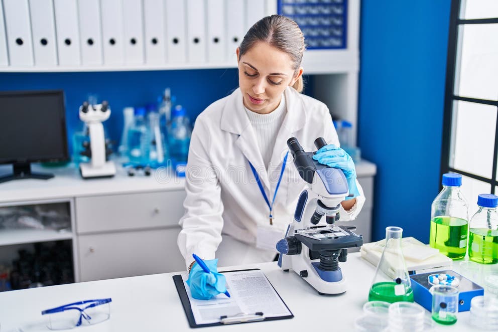 Young Woman Scientist Using Microscope Writing on Report at Laboratory ...