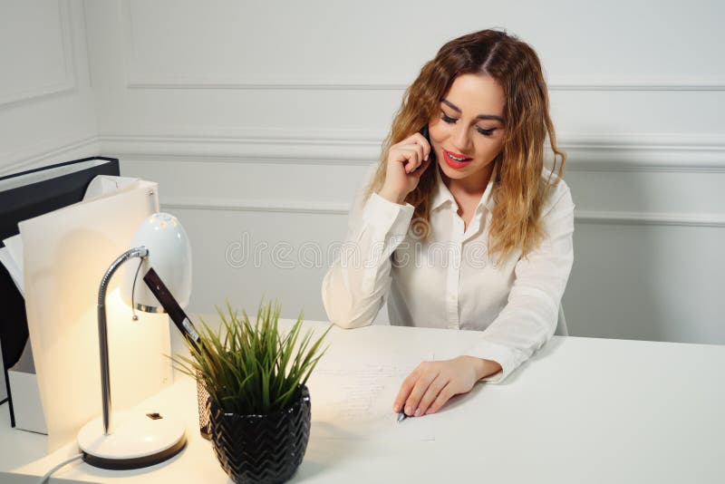 Young Woman Secretary is Talking on Mobile Phone and Taking Notes ...