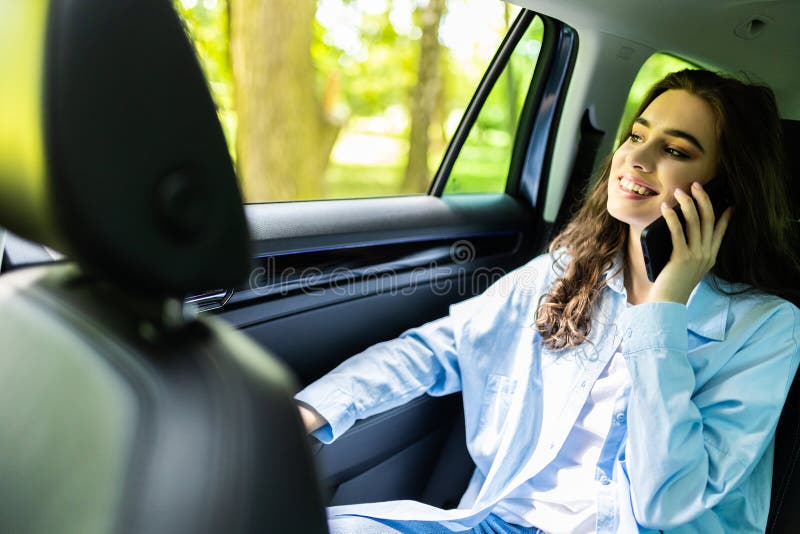 Young Woman Sitting in the Car and Looking at Mobile Phone in Hands ...