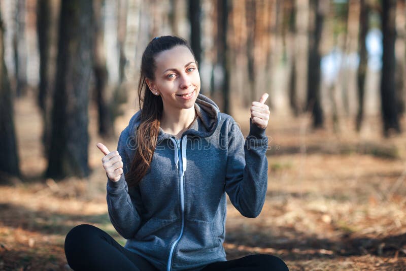 Young Woman Sitting on the Grass in the Forest on Sunny Day, Shows ...