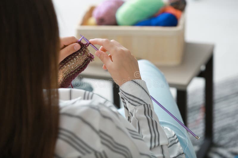 Young Woman Sitting On Sofa And Knitting Warm Sweater At Home Stock