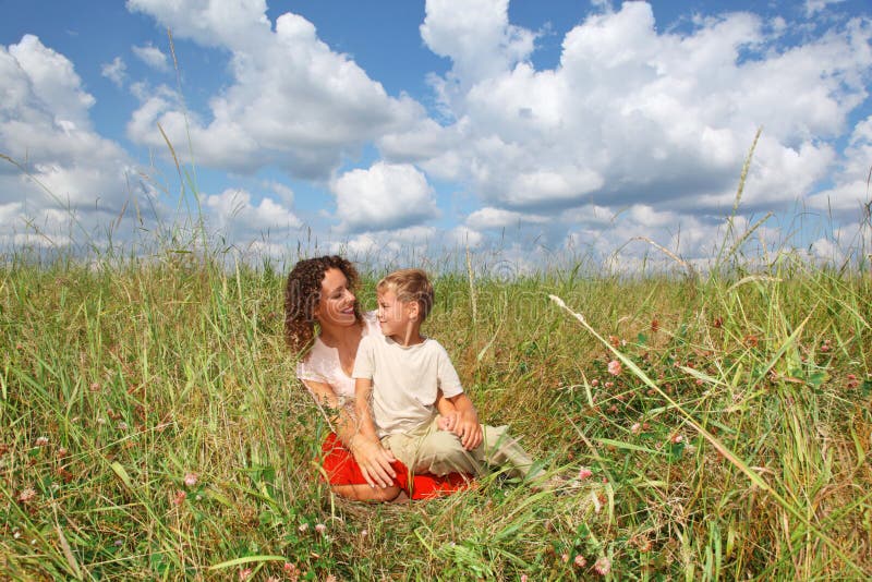 Young Woman and Smiling Boy Sitting on Meadow Stock Image - Image of ...