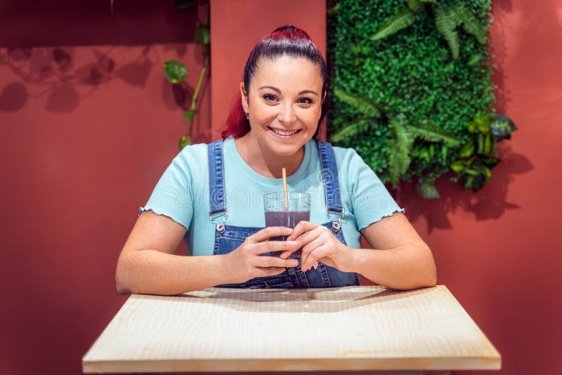 Young Woman Smiling At Camera While Drinking A Fresh Smoothie At A