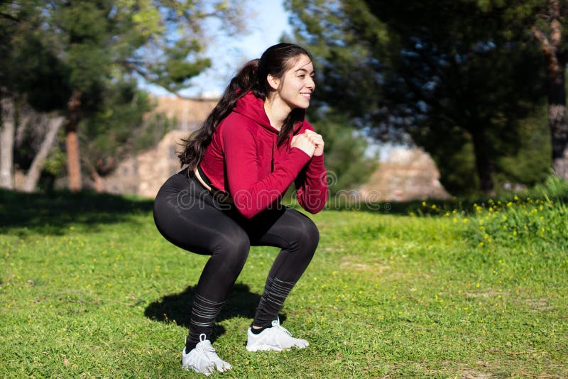 Young Woman Smiling and Doing Squats in a Park. Training and Health ...