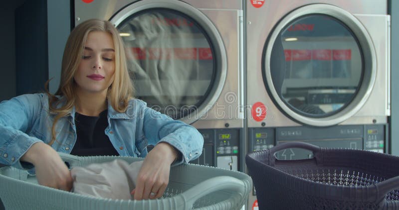 Young Woman Sorting Clothes for Washing Standing in the Self Service ...
