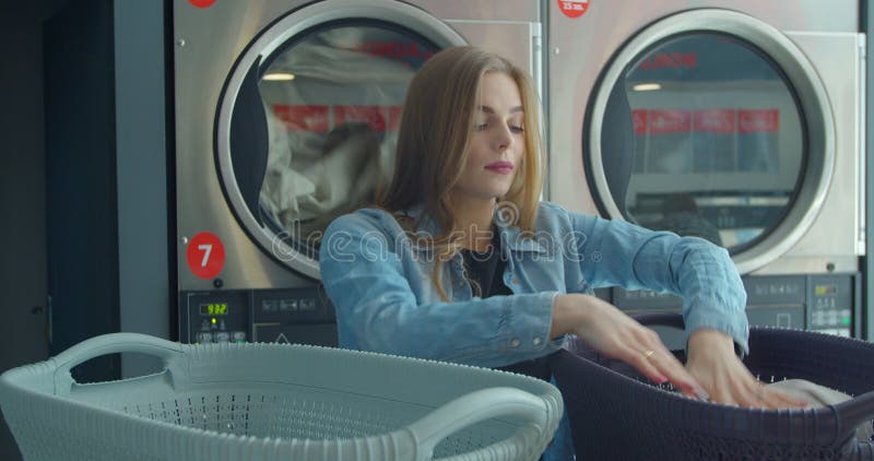 Young Woman Sorting Clothes for Washing Standing in the Self Service ...