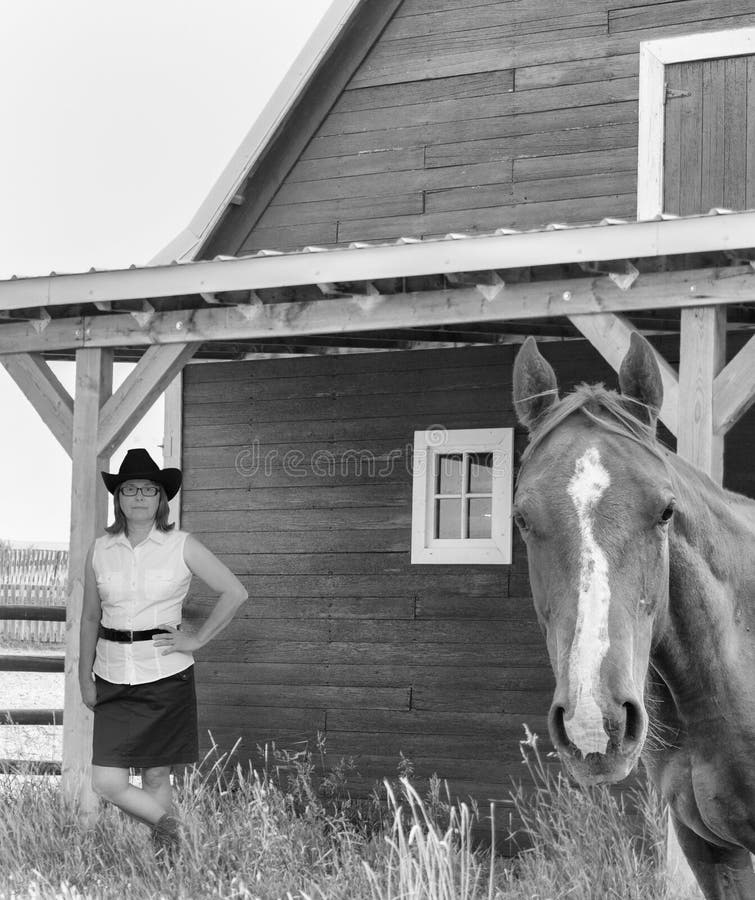 Young Woman Standing by a Barn with a Horse in Foreground Stock Photo ...