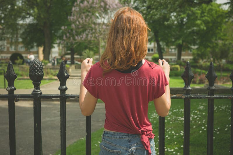 Young Woman Standing by Gate Outside Park Stock Image - Image of ...