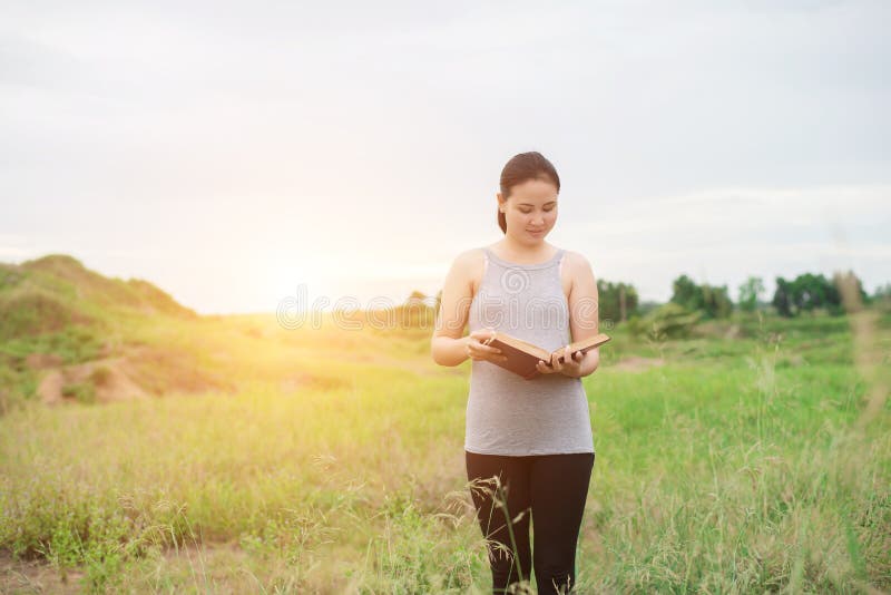 Young Woman Standing Reading Book at Meadows. Stock Photo - Image of ...