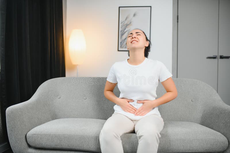 Young Woman Suffering from Abdominal Pain at Home. Gynecology Concept ... Young Woman Suffering from Abdominal Pain at Home. Gynecology Concept ...