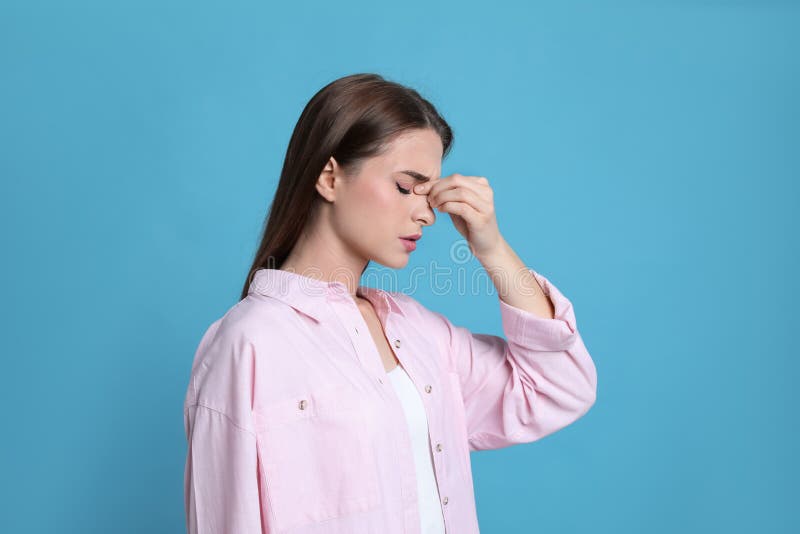 Young Woman Suffering from Headache on Light Blue Background Stock ...