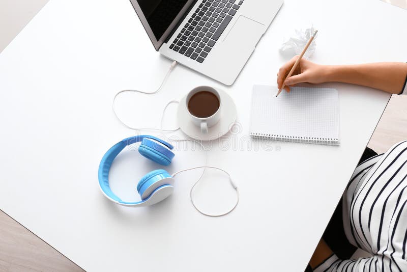 Young Woman Taking Notes at Table with Laptop and Headphones Stock ...