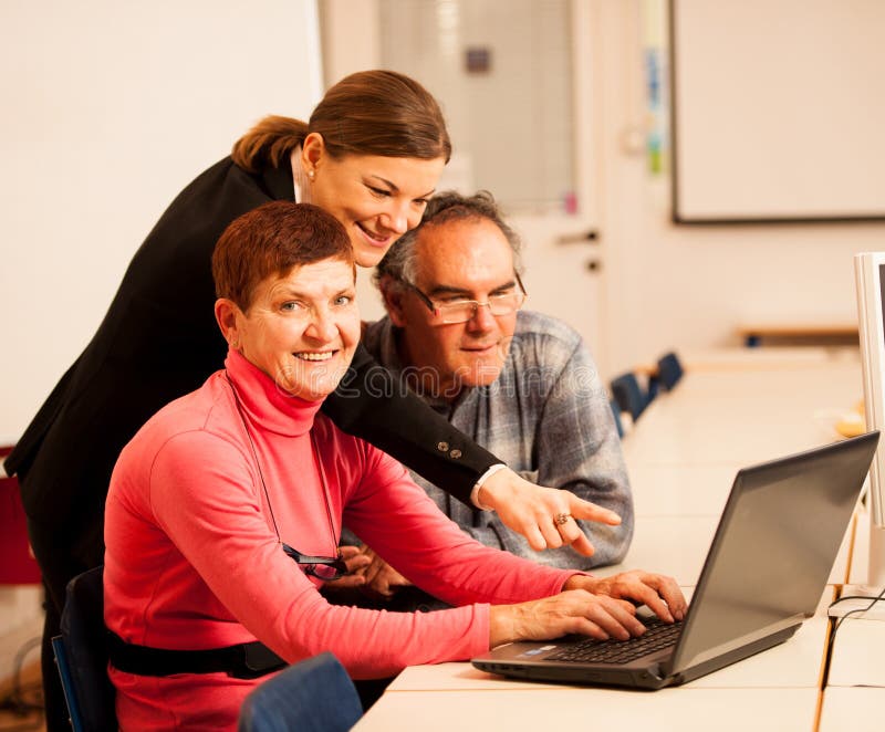 Young Woman Teaching Elderly Couple of Computer Skills ...