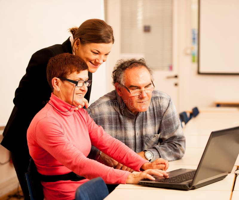 Young Woman Teaching Elderly Couple of Computer Skills ...