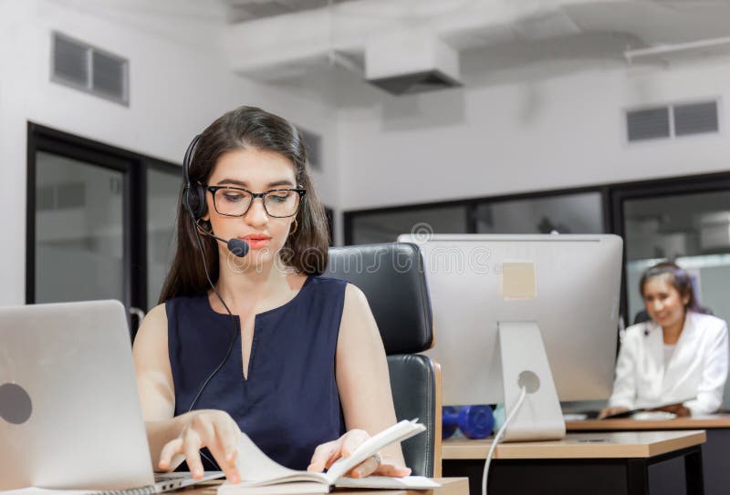 Young Woman Telephone Operator with Headset Working on Laptop Computer ...