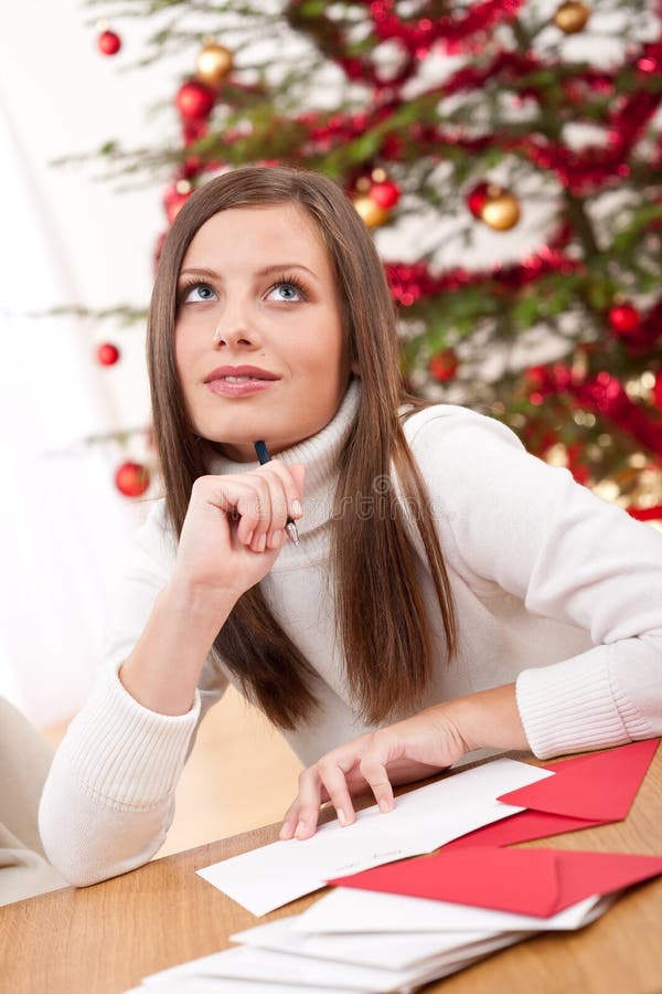 Young Woman Thinking while Writing Christmas Card Stock Image - Image ...