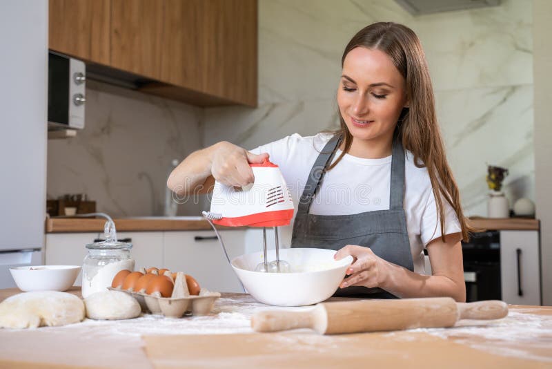 Young Woman Uses Mixer in Beating Eggs, Stands in a Modern Kitchen ...