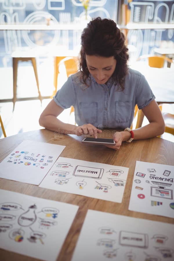 Young Woman Using Digital Table while Sitting at Table with Chart ...