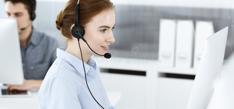 Young Woman Using Headset and Computer while Talking with Customers ...